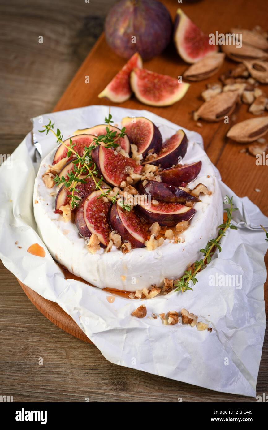 Brie cheese served on a wooden board with figs, walnuts and honey Stock ...