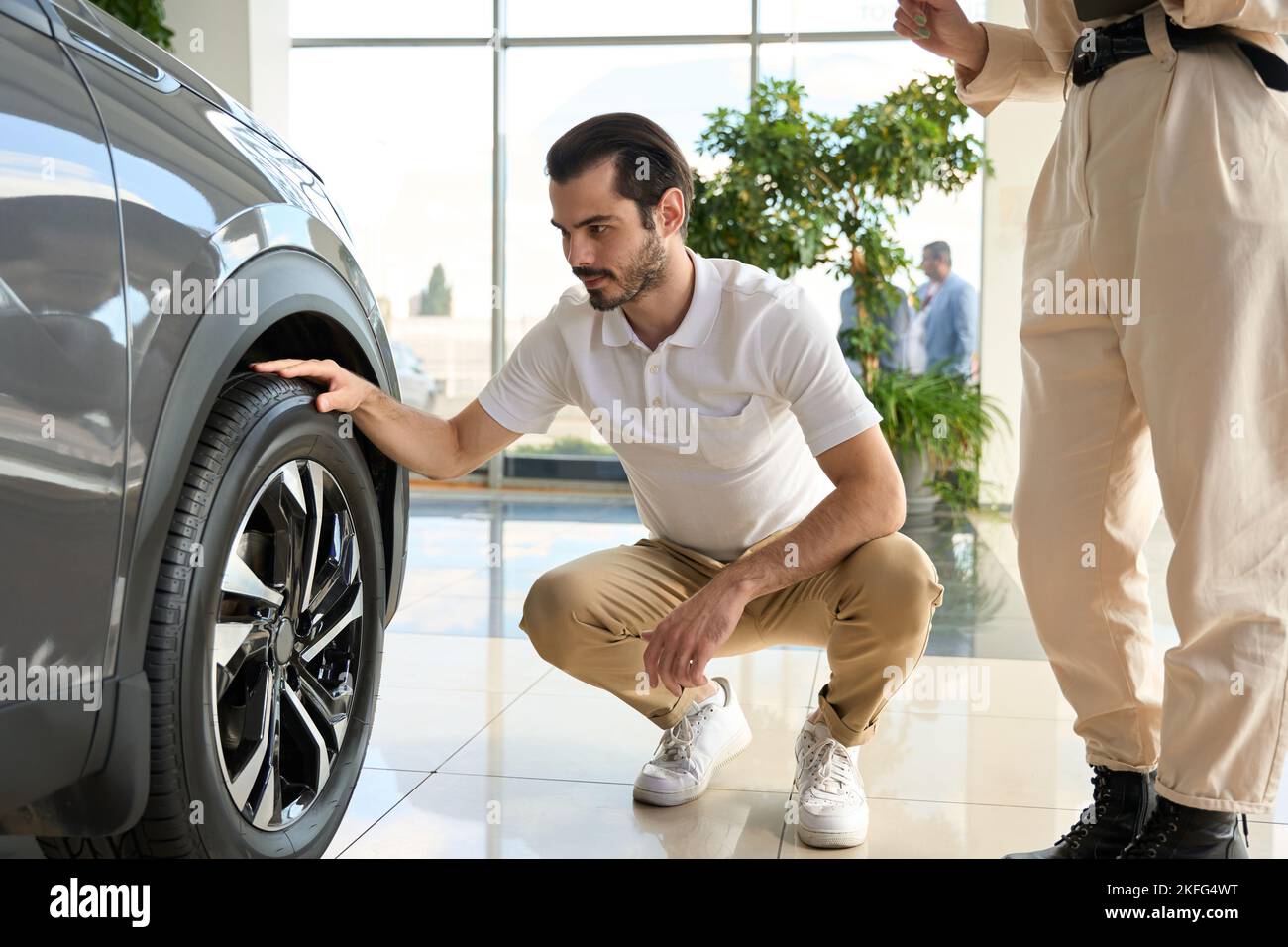 Concentrated car dealership client checking tyre quality Stock Photo ...