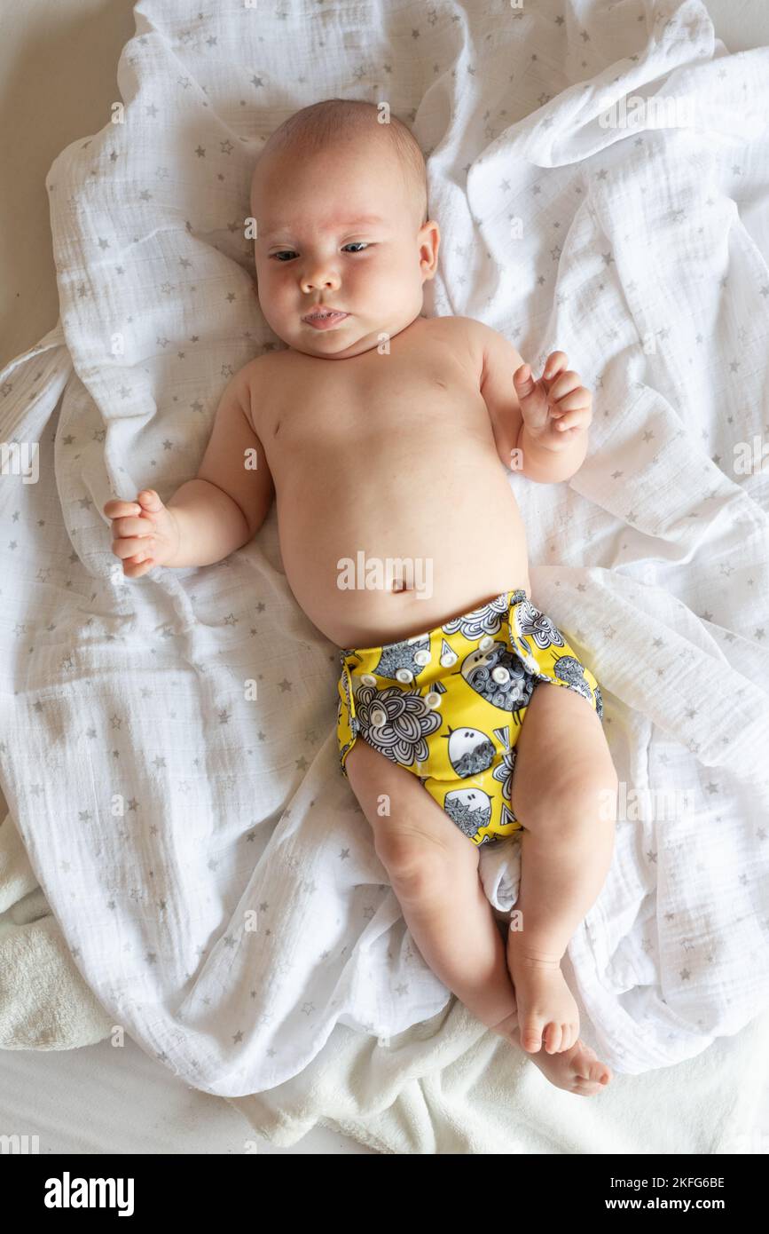 A happy, content baby girl lying on her back. She is wearing a modern ...