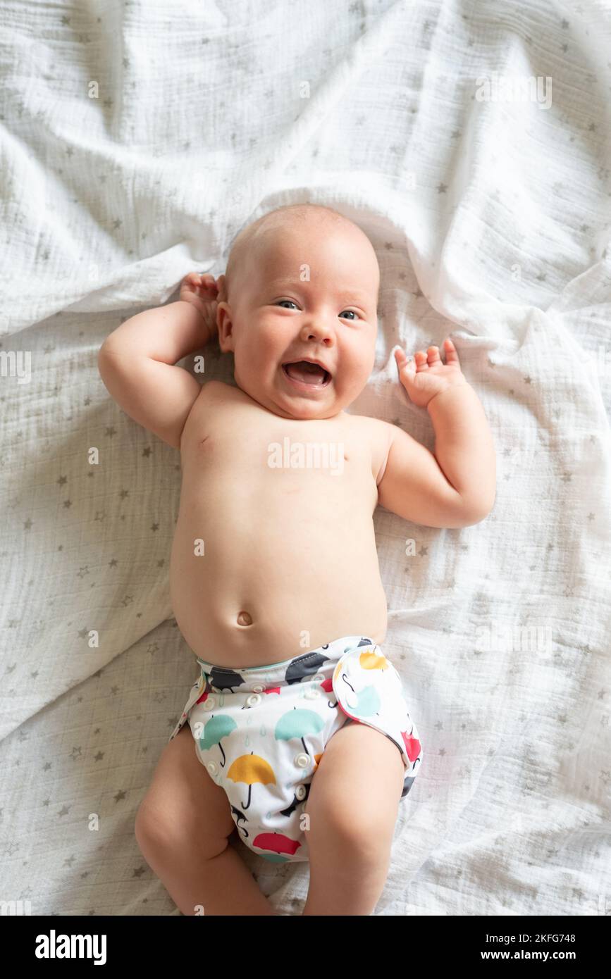 A happy, content baby girl lying on her back. She is wearing a modern ...