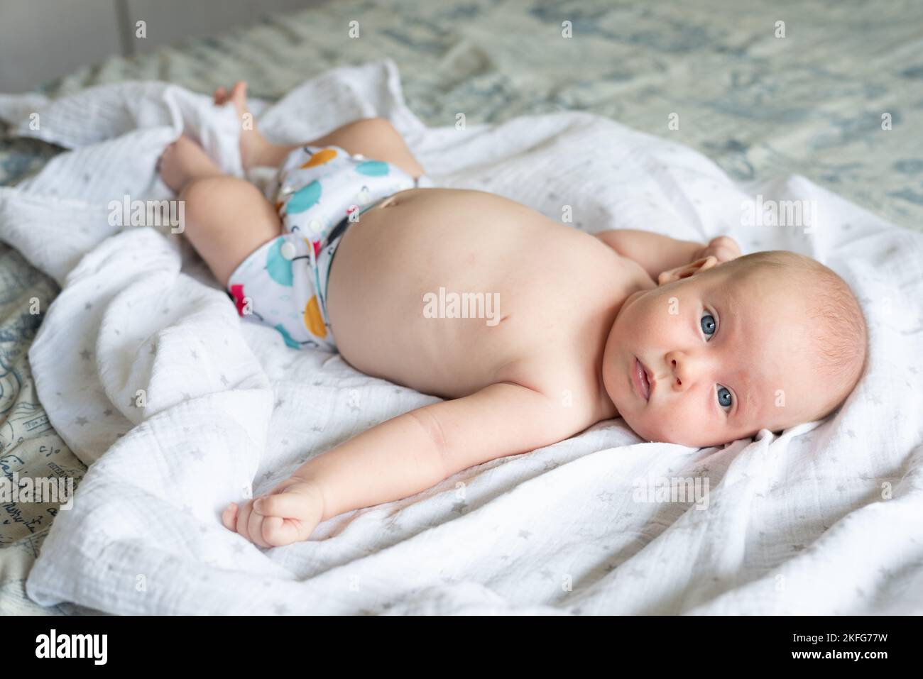 A happy, content baby girl lying on her back. She is wearing a modern ...