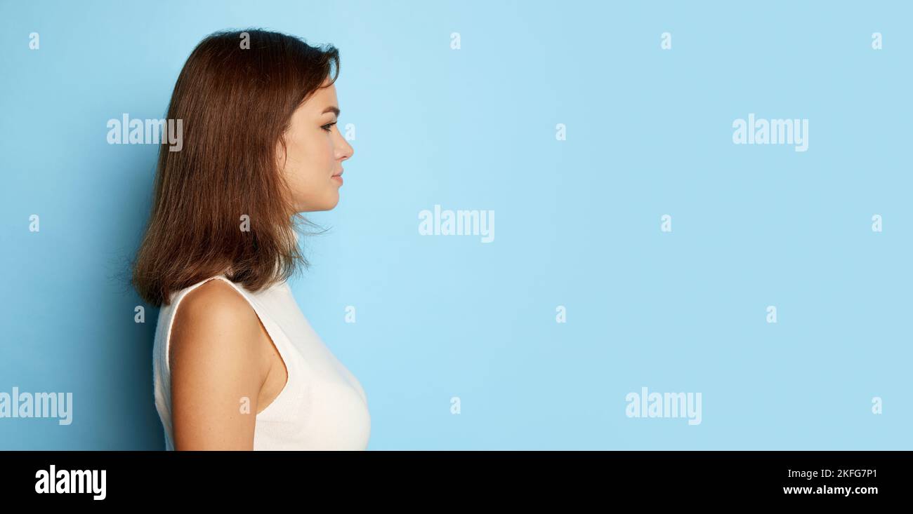 Side view portrait of young beautiful woman posing isolated over blue ...