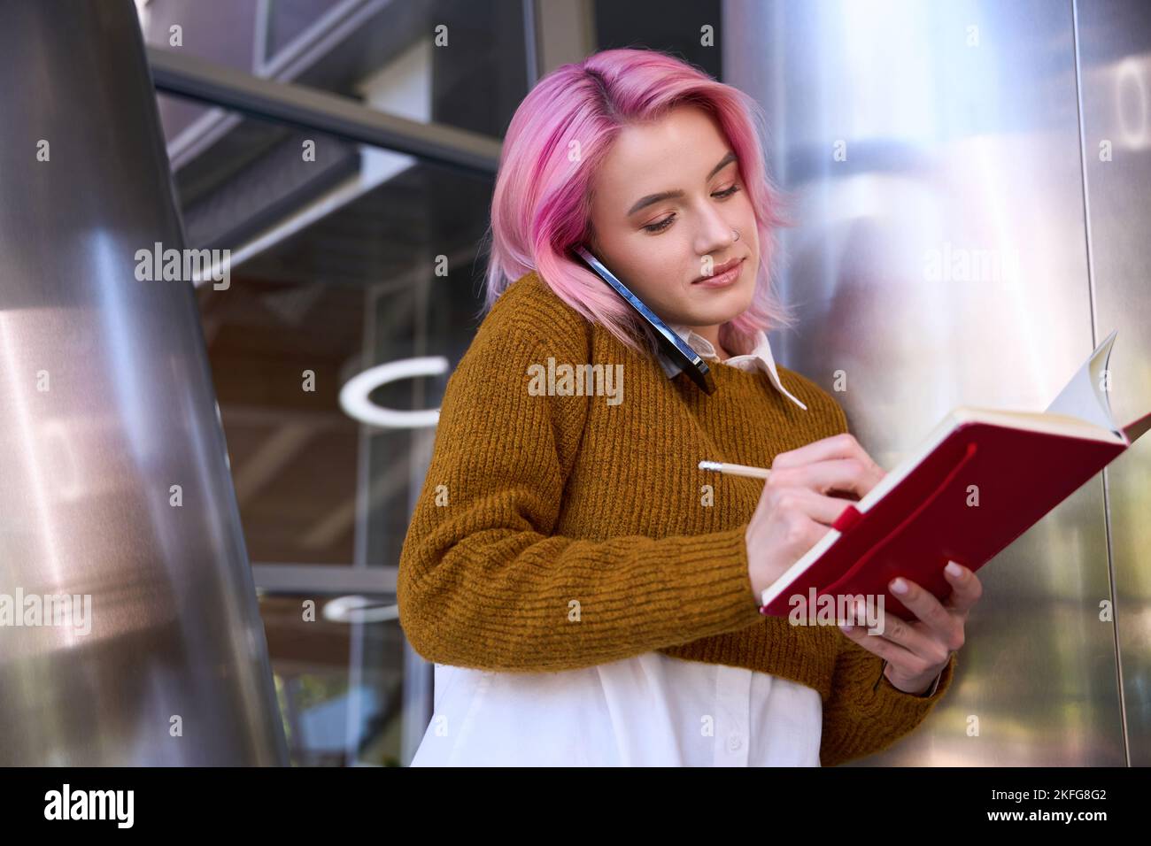 Lady making notes and talking on the phone Stock Photo - Alamy