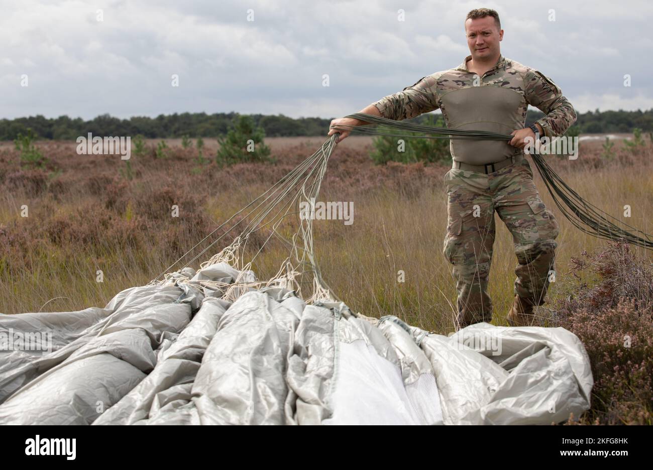 A U.S. Army Paratrooper gathers up his assigned parachute during ...
