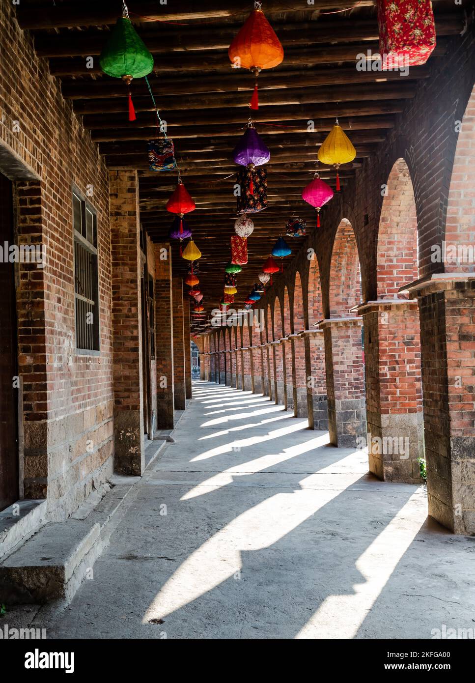 A vertical shot of colorful lanterns and umbrellas over narrow alley of ...