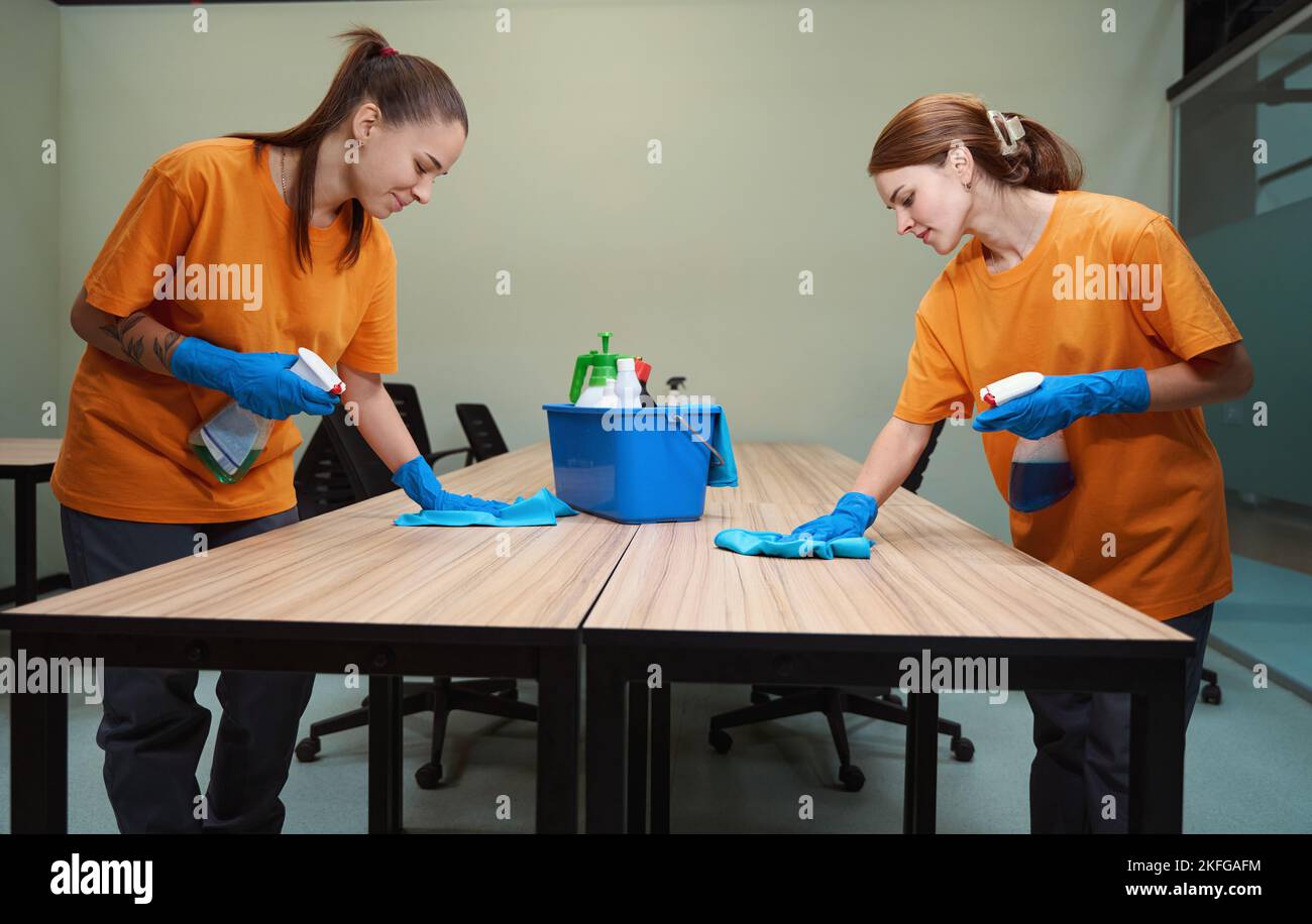 Cleaning company teammates working together while wiping the table ...