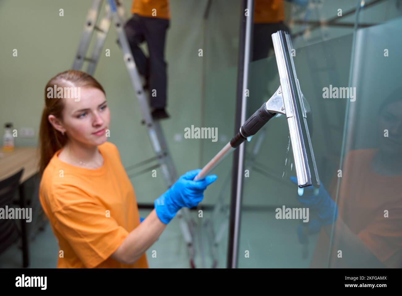 Hard-working woman cleaning a transparent surface with special mop ...