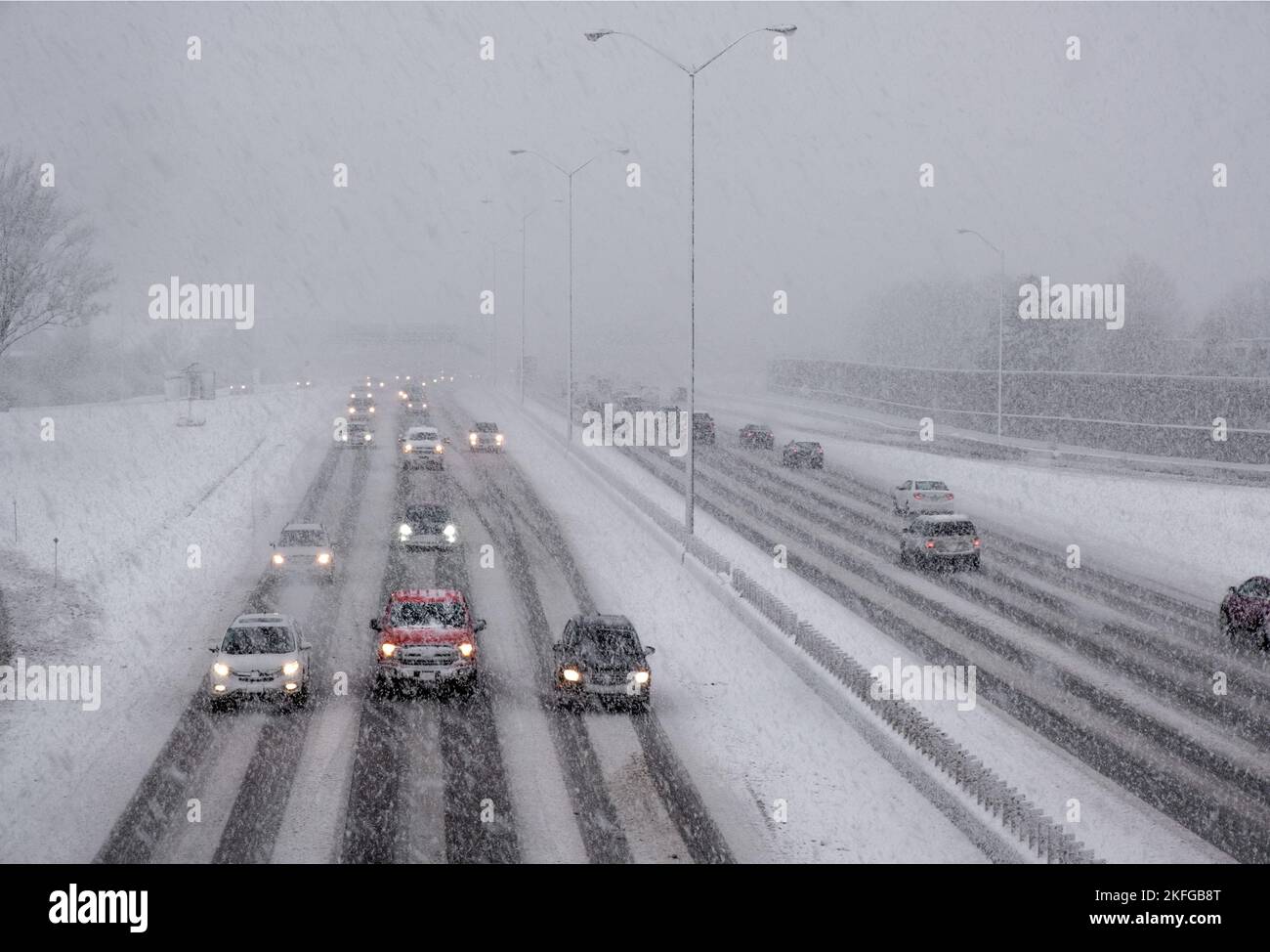 A high-angle shot of cars driving in a blizzard on a multi-lane highway ...