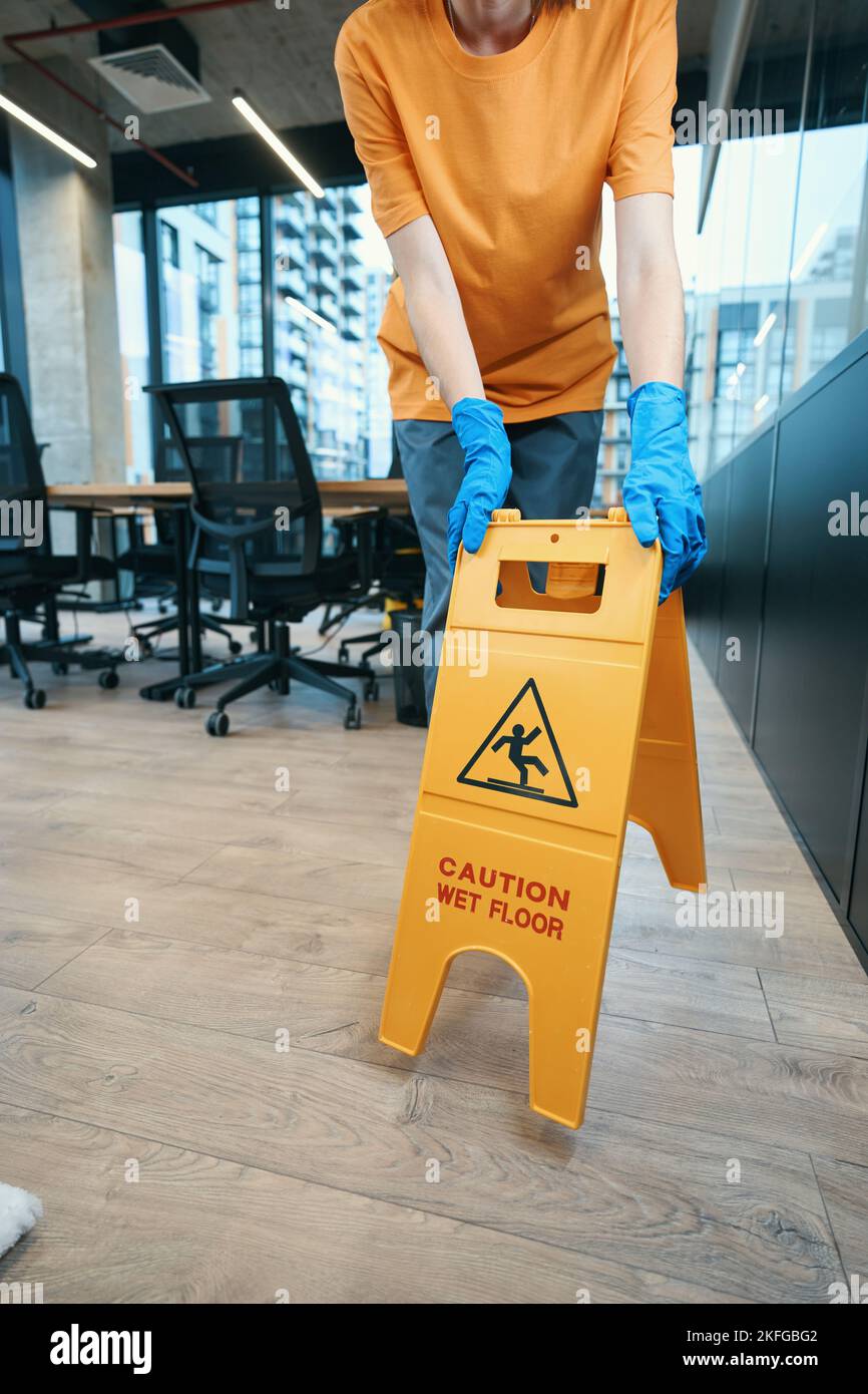 Janitor putting wet floor warning sign in office area Stock Photo - Alamy