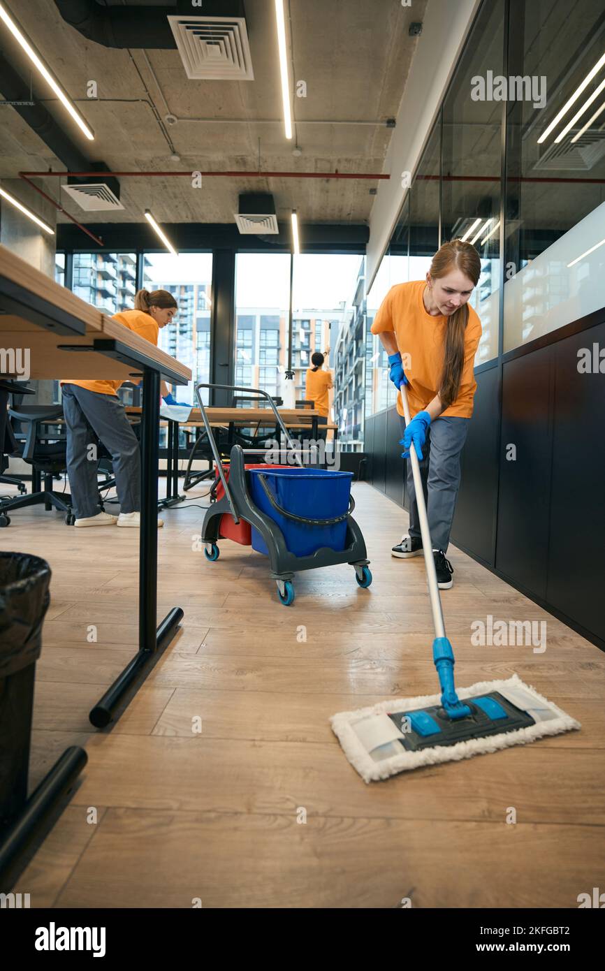 Team cleaning ladies works in coworking area, women use mop, buckets ...