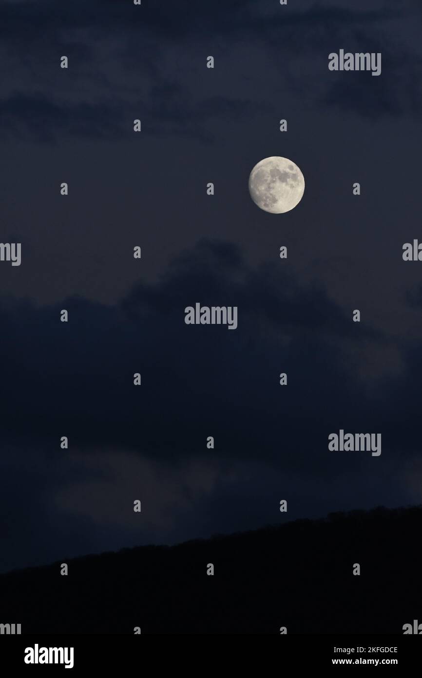 The mysterious full moon in the dark night sky, in a vertical shot ...