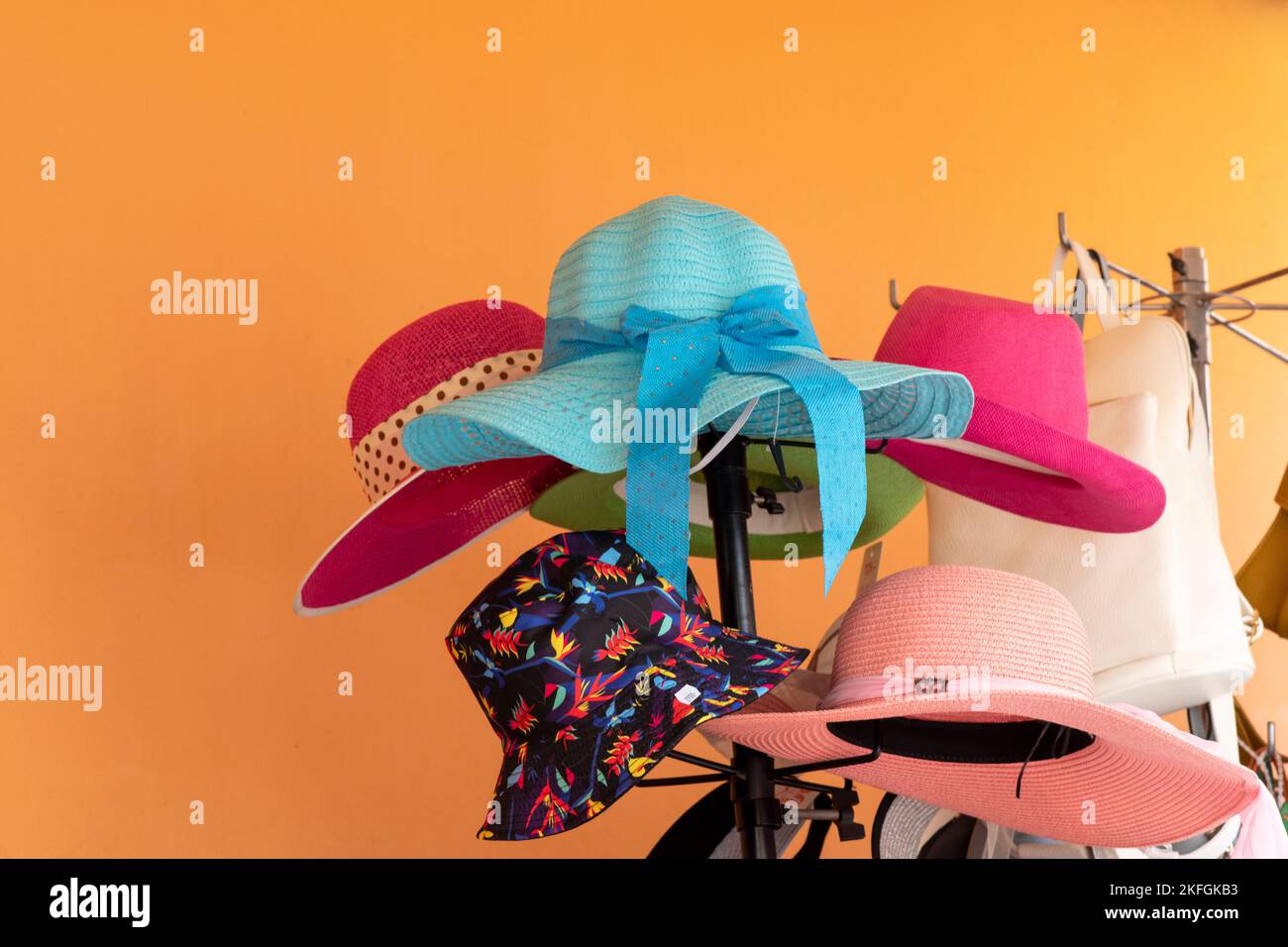 Collection of colorful summer hats hanged on a hat rack against bright ...
