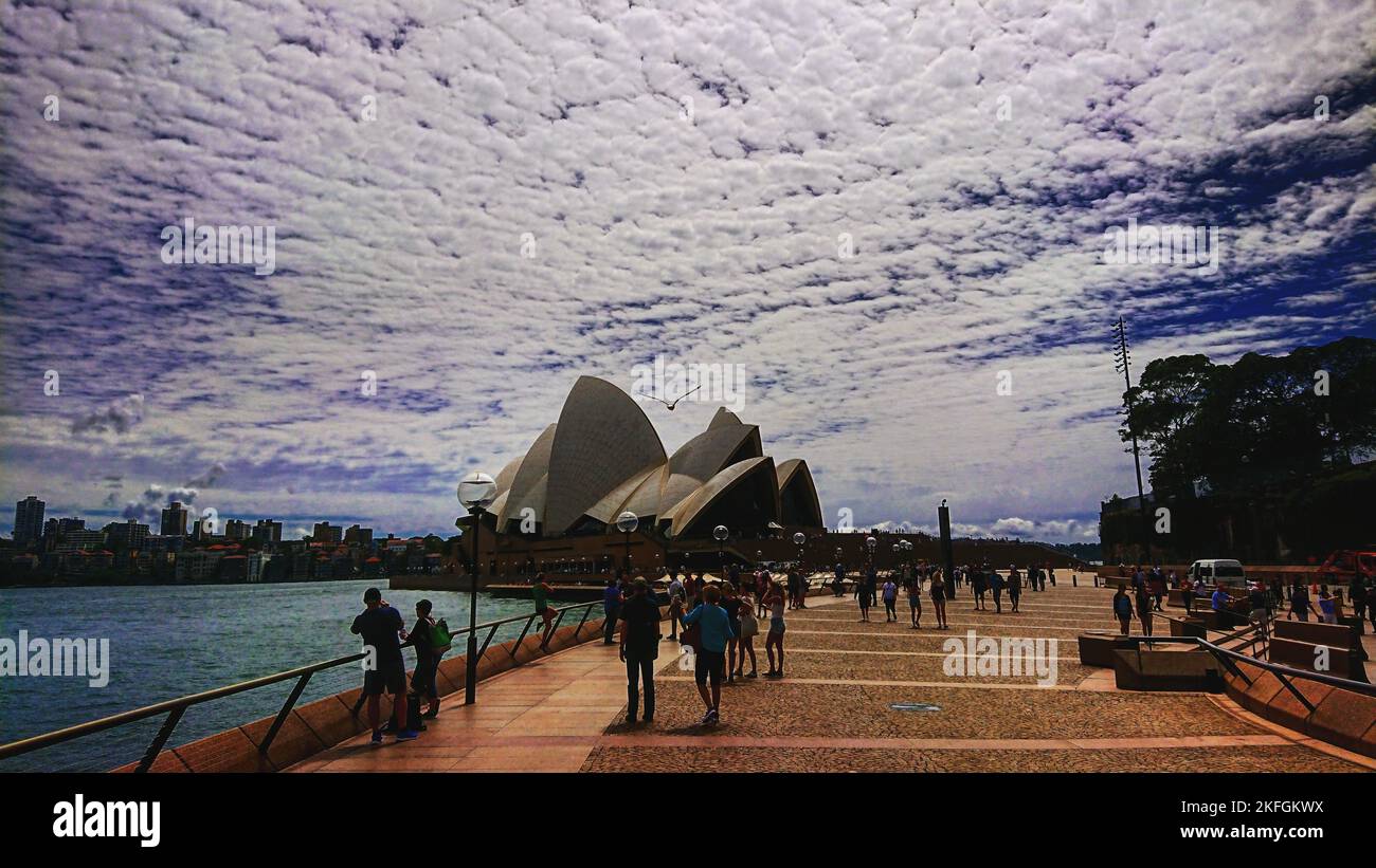 The view of people walking by the Sydney Opera House building under the ...