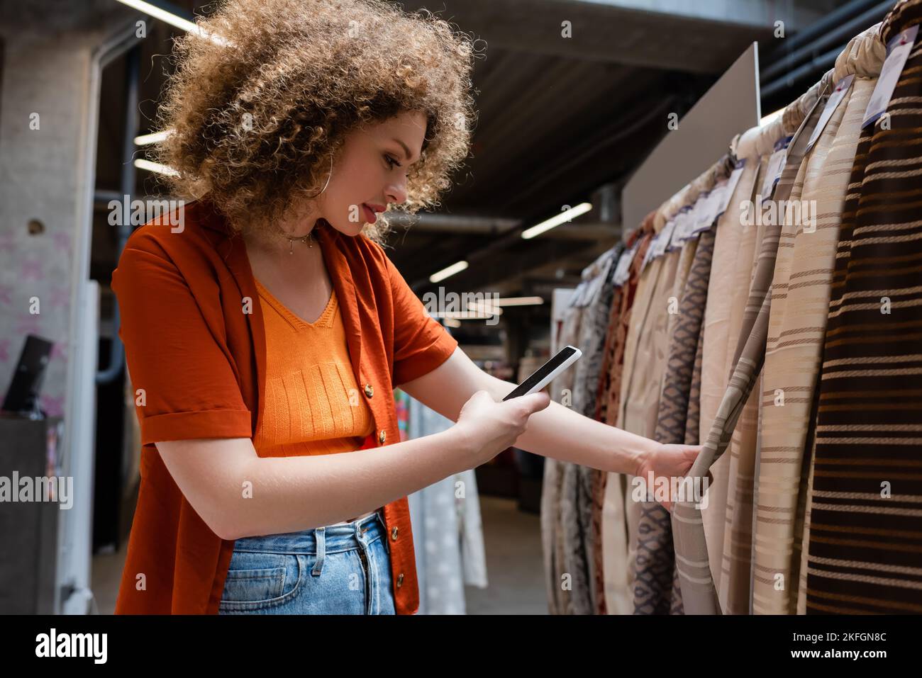 Side view of pretty customer taking photo on smartphone while touching ...