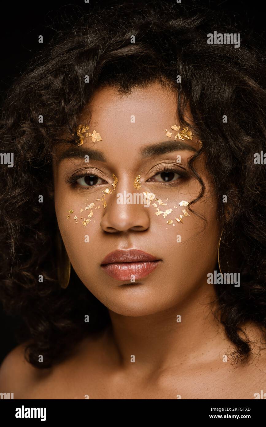 brunette african american woman with golden body paint on cheeks ...