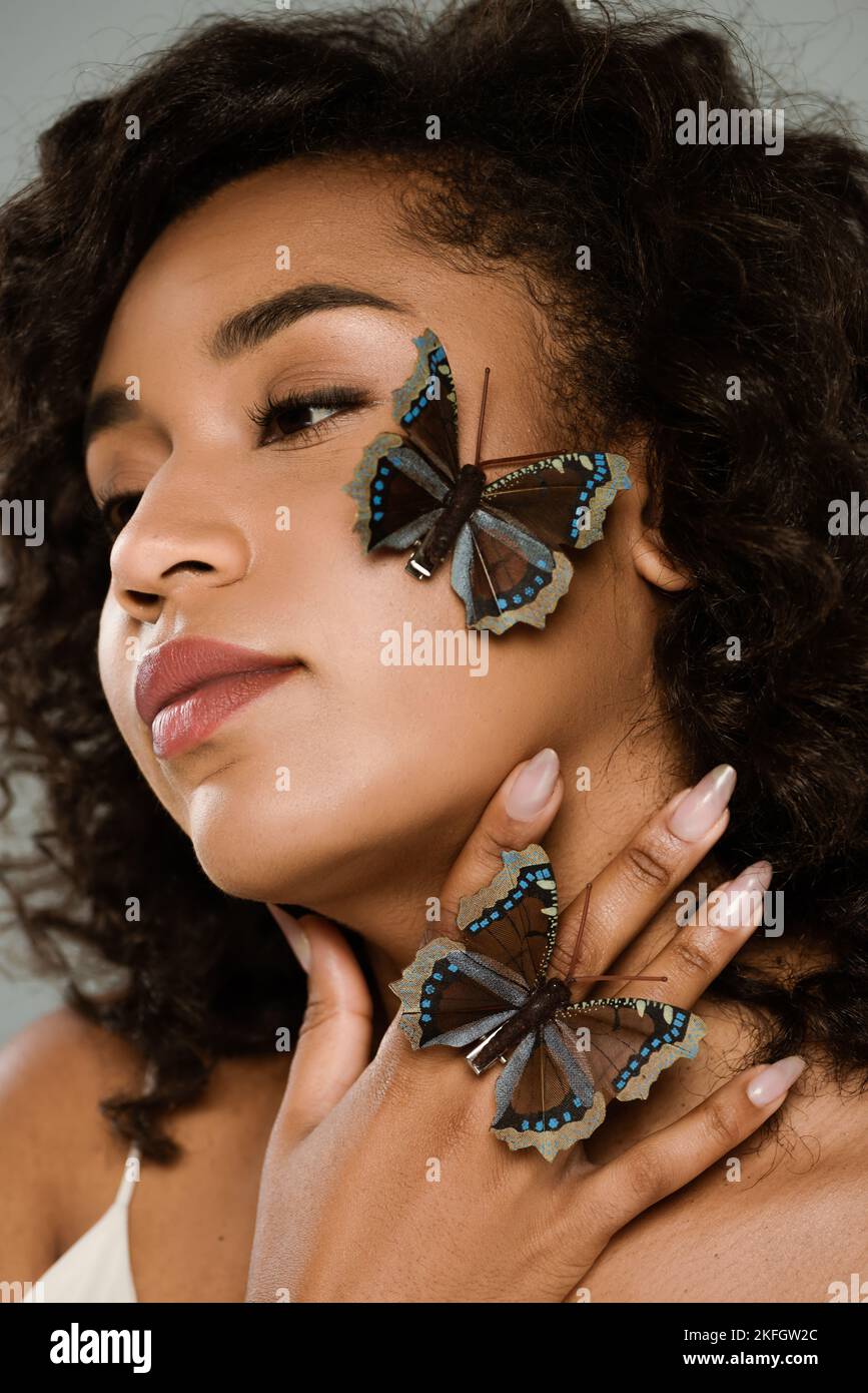 curly african american woman with butterflies on hand and face looking ...
