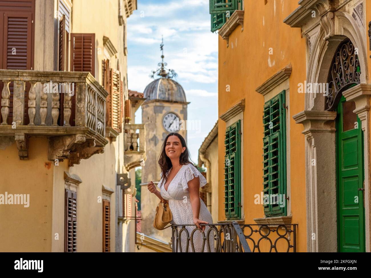 A Caucasian young woman wearing white dress in street of old town in ...