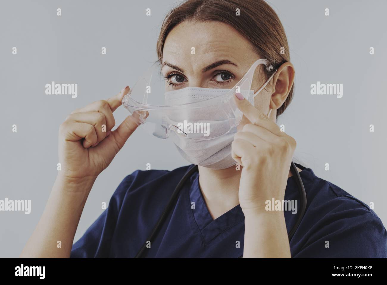 Female doctor putting on surgical face mask and medical goggle Stock ...