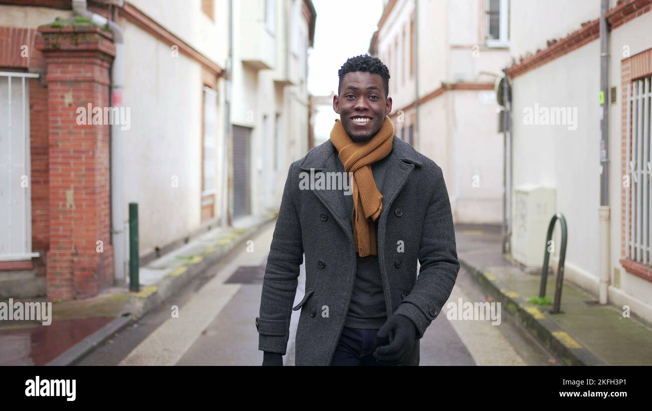 Happy black African man walking outside in European city smiling Stock ...