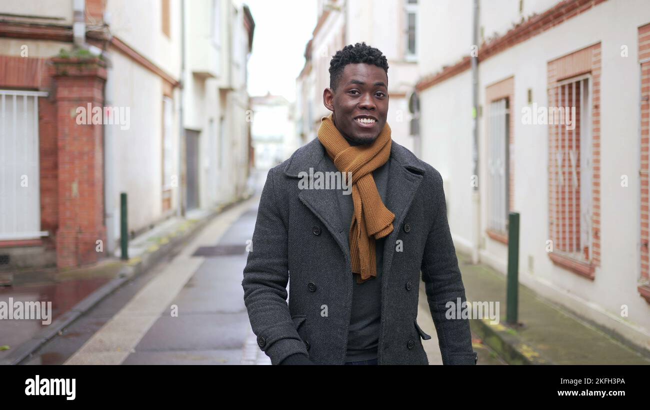 Happy black African man walking outside in European city smiling Stock ...