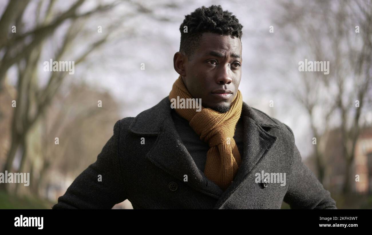 Elegant black man walking outside in nature park during winter season ...