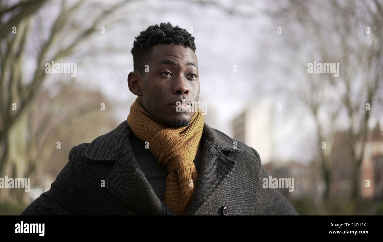 Elegant black man walking outside in nature park during winter season ...