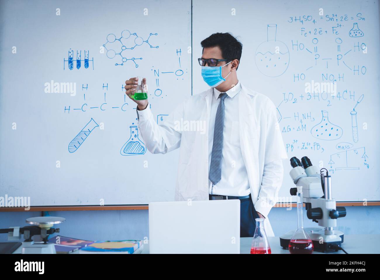 Science teacher wearing a mask stands to teach science class in the ...