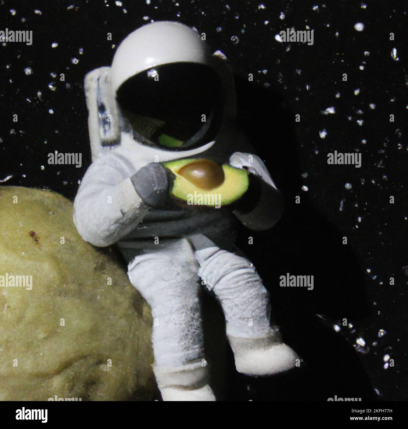 A closeup view of a figure of an astronaut eating avocado on the moon ...