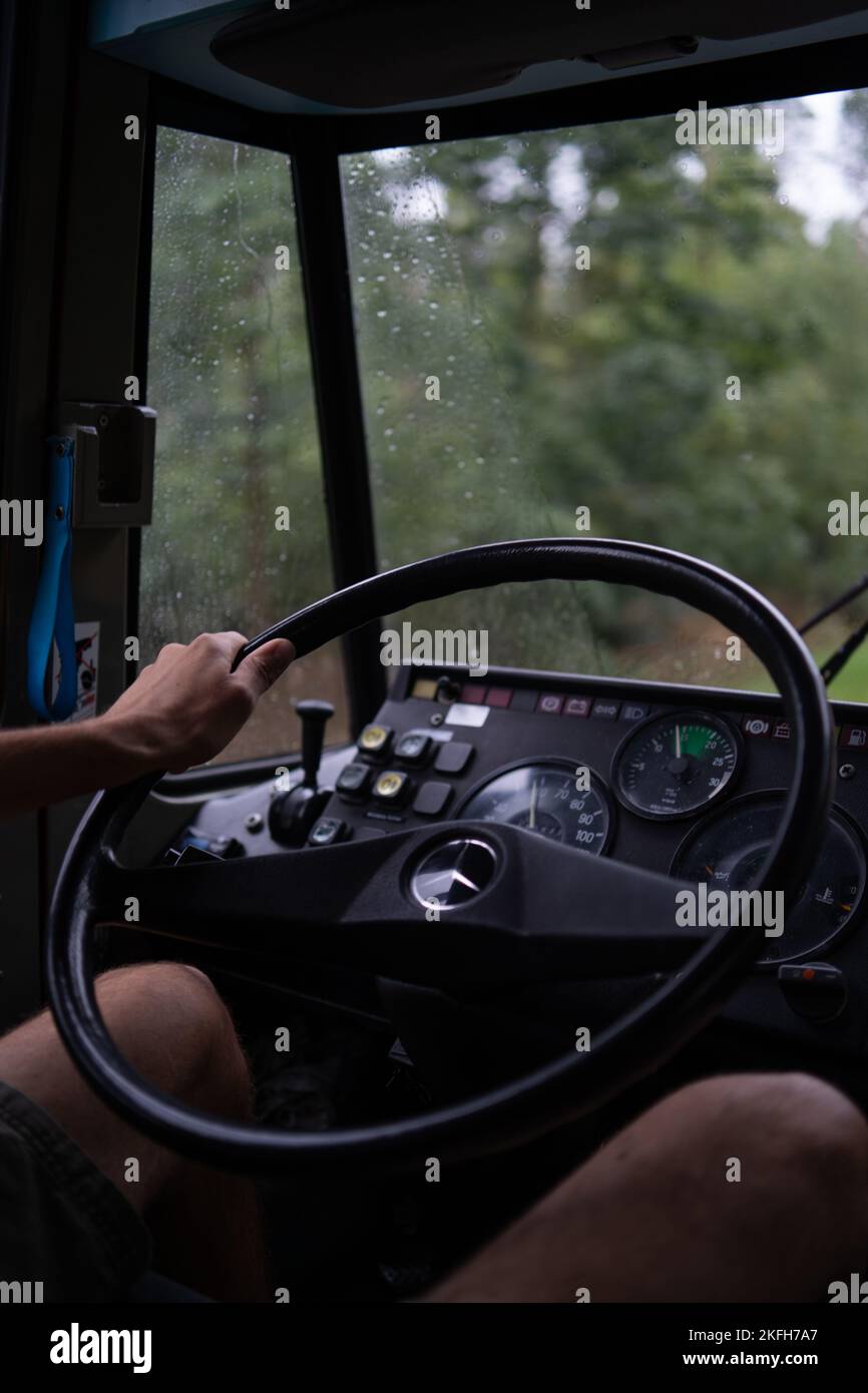 A vertical shot of a man holding the steering wheel of an old Mercedes ...