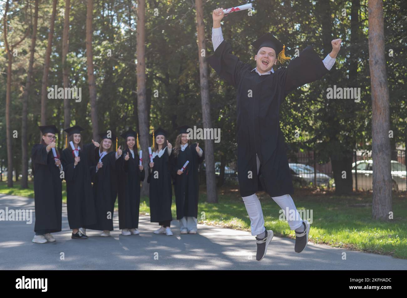 Happy young caucasian man celebrating graduation. Crowd of students ...