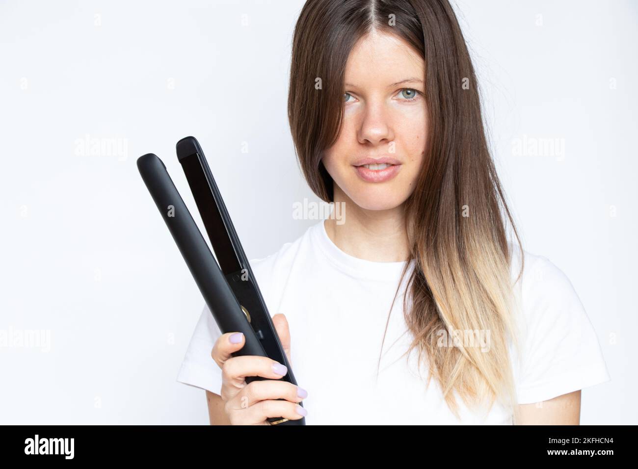 The Girl Straightens Her Hair With Straightening Tongs On A White