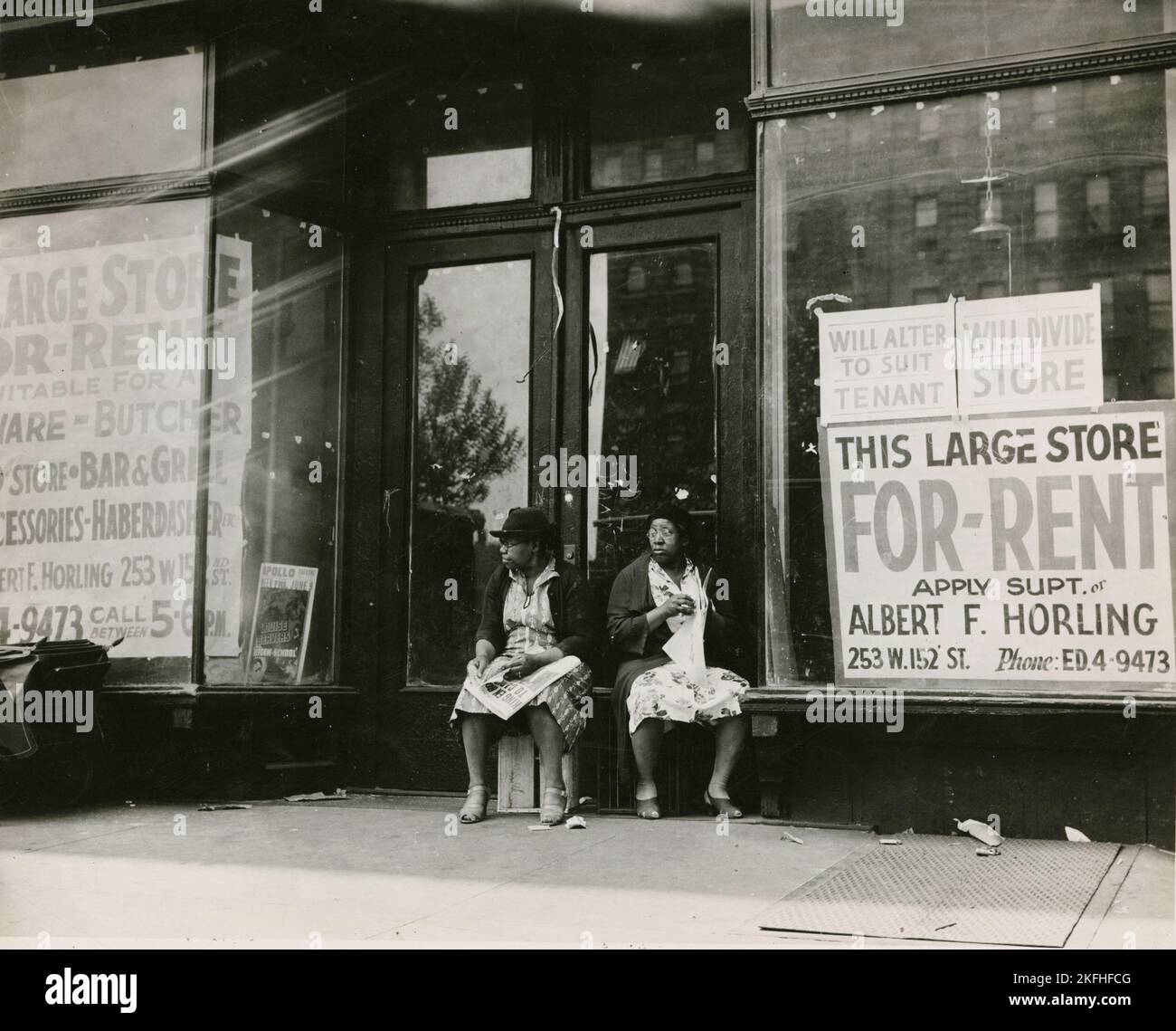 Sidewalk sitters. Two women sitting in doorway of empty storefront that ...