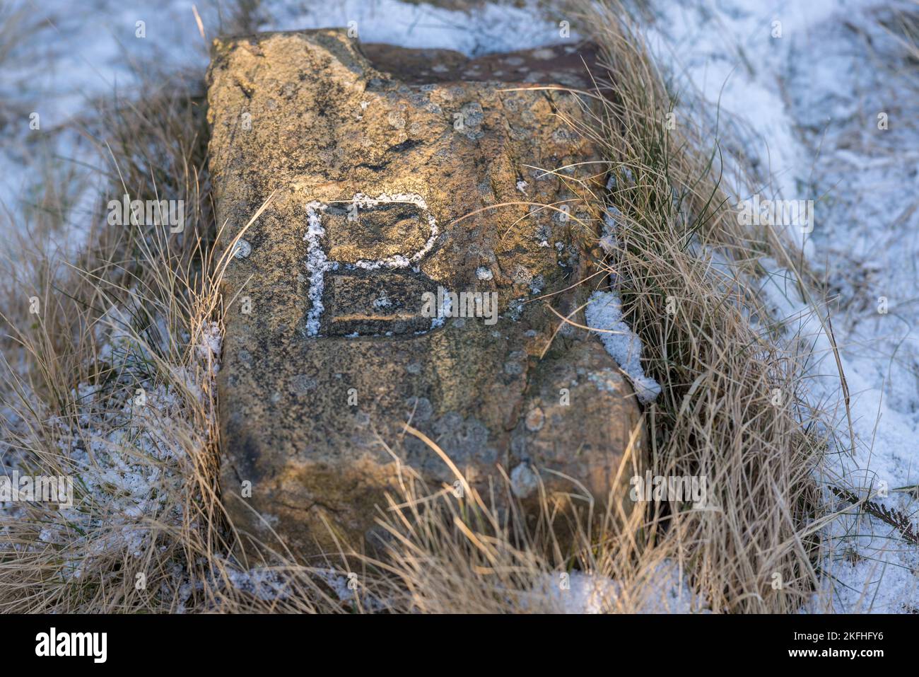 Old quarry stone with a letter B carved into it. Some snow in the ...