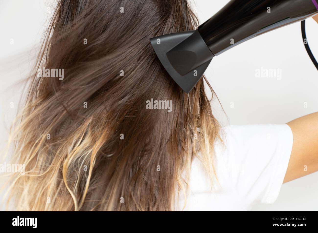 The girl dries her hair with a hairdryer on a white background, hair ...