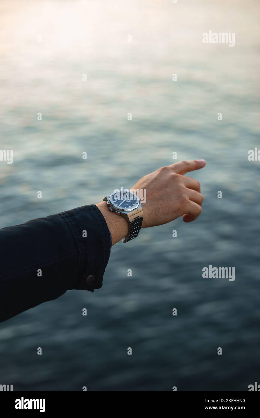 A male hand with a wristwatch pointing on sea background Stock Photo ...