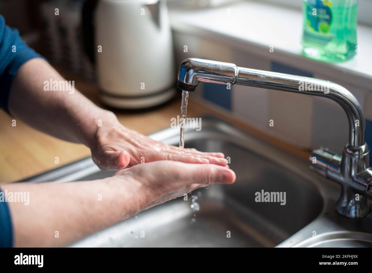 Man washing hands using soap and running water by the kitchen sink ...