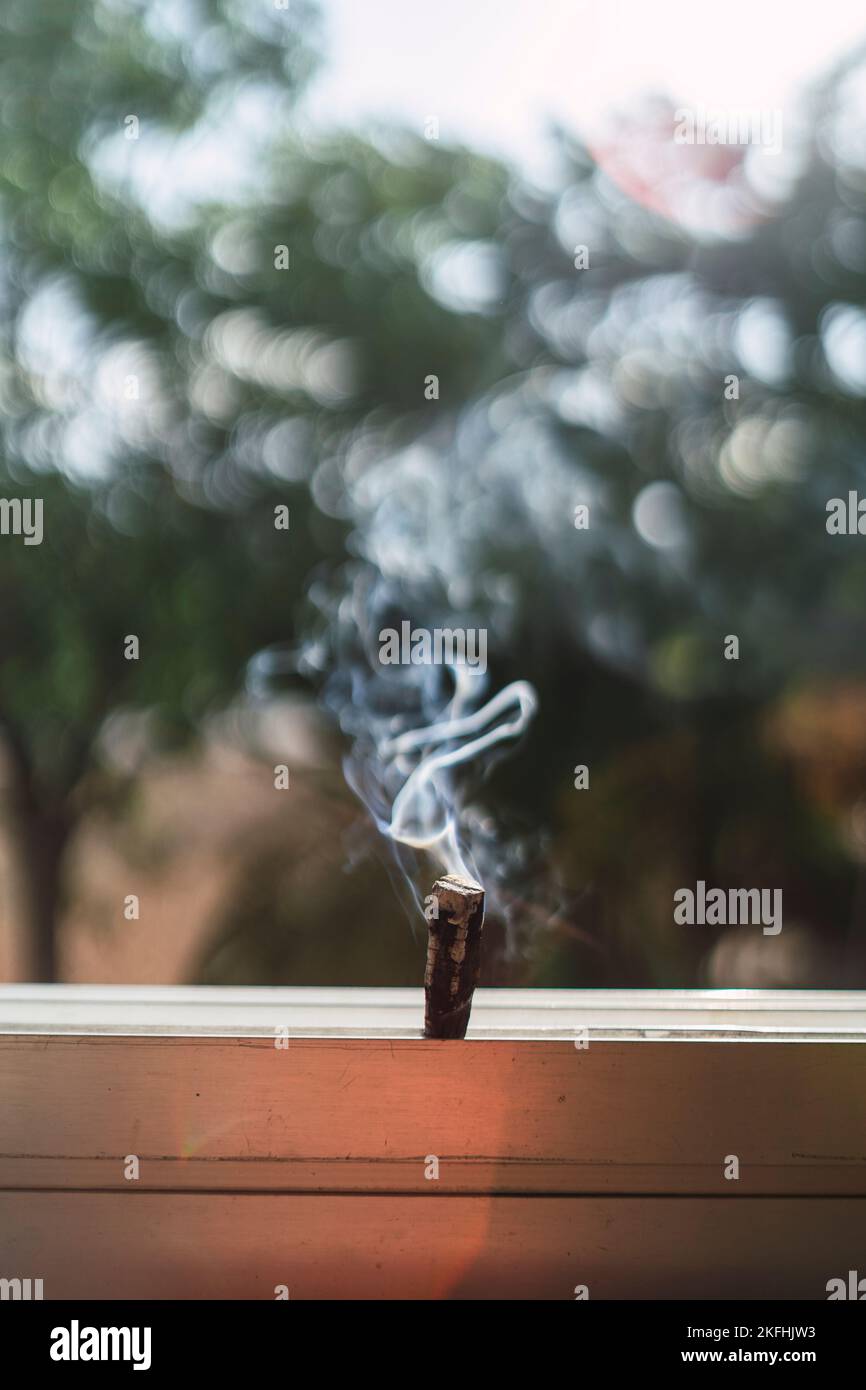 A vertical closeup of Palo Santo burning on a window frame Stock Photo ...