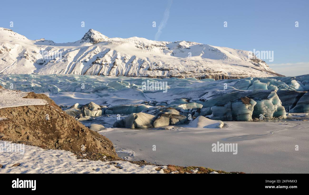 Icelandic glacial field with rugged snow covered mountains and blue sky ...