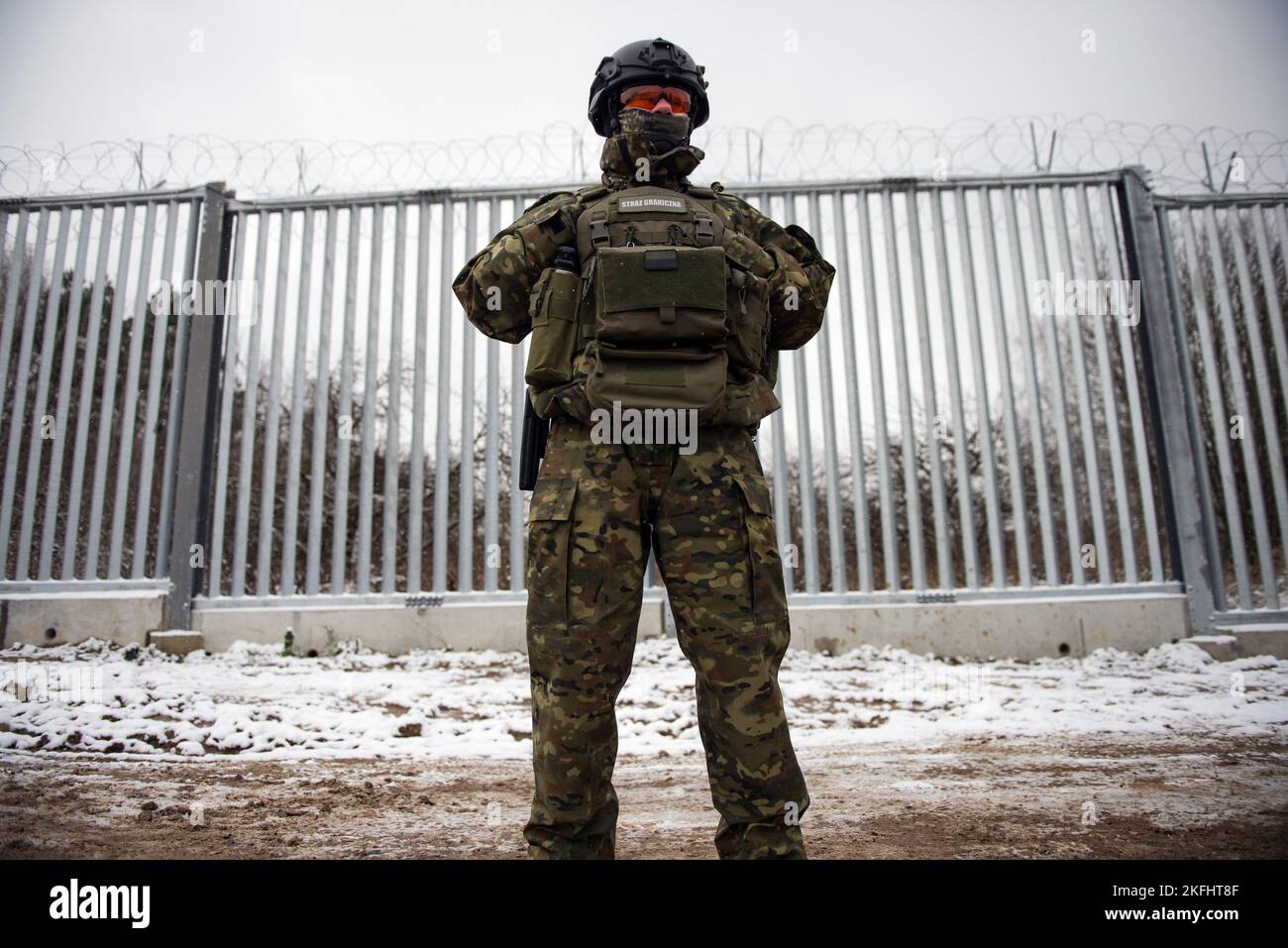 A border guard is seen guarding the border wall dividing Poland from ...