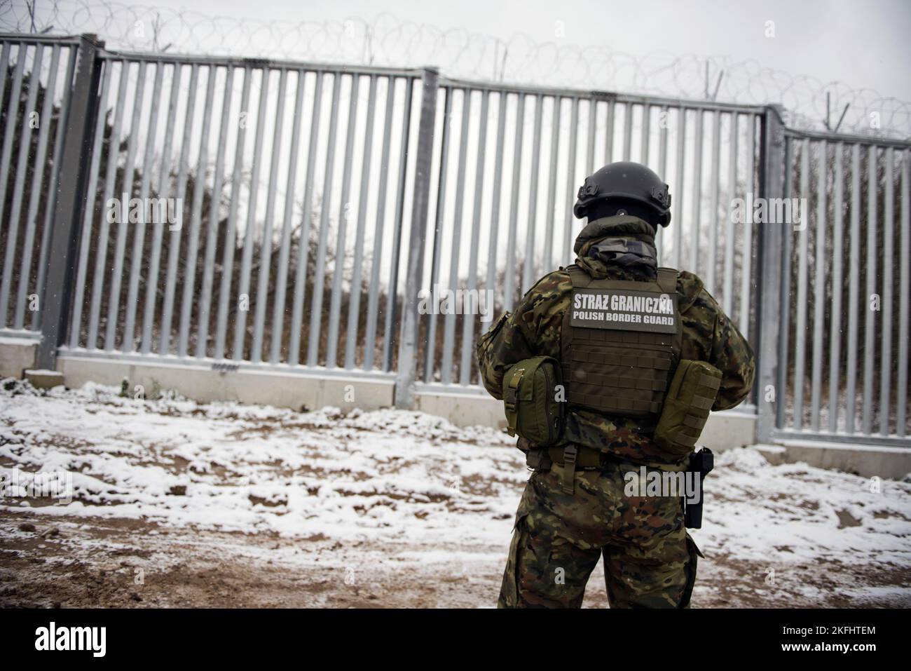 A border guard is seen guarding the border wall dividing Poland from ...