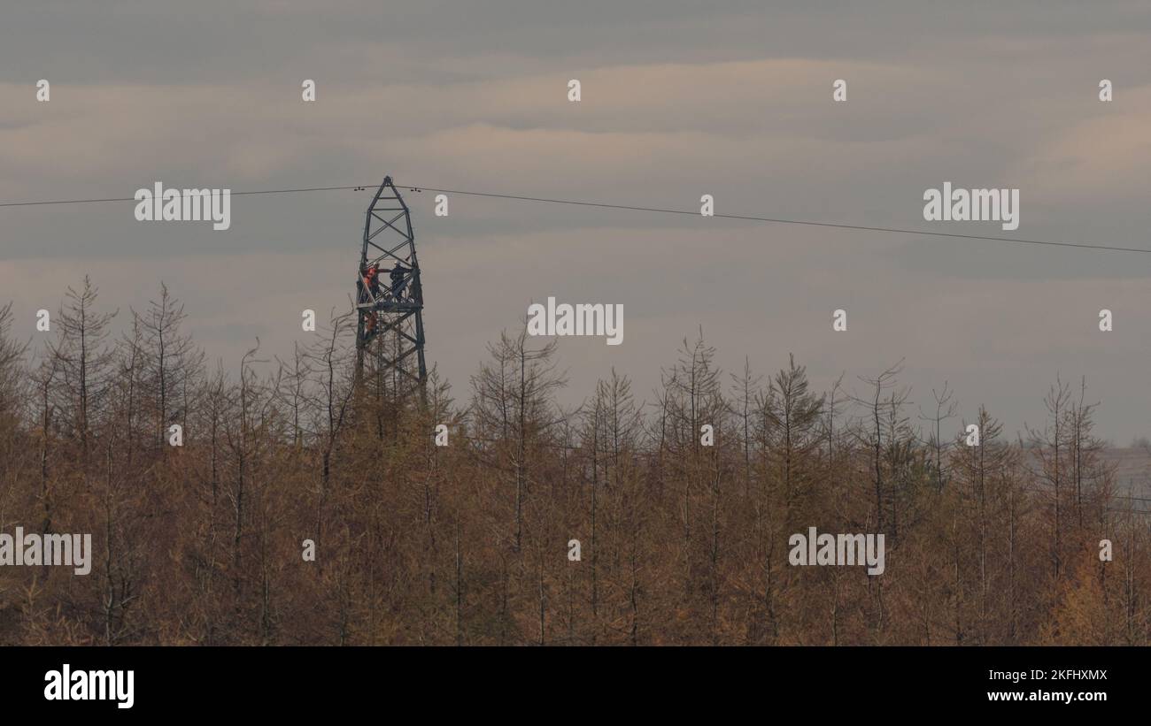 Electricity workers working high up on Electricity pylon and over head ...