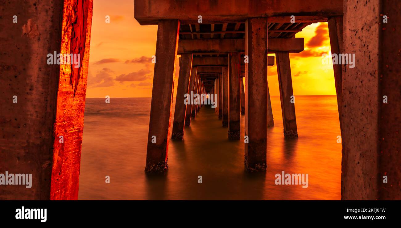 The poles of the beautiful Old Naples Pier over water in Florida at ...