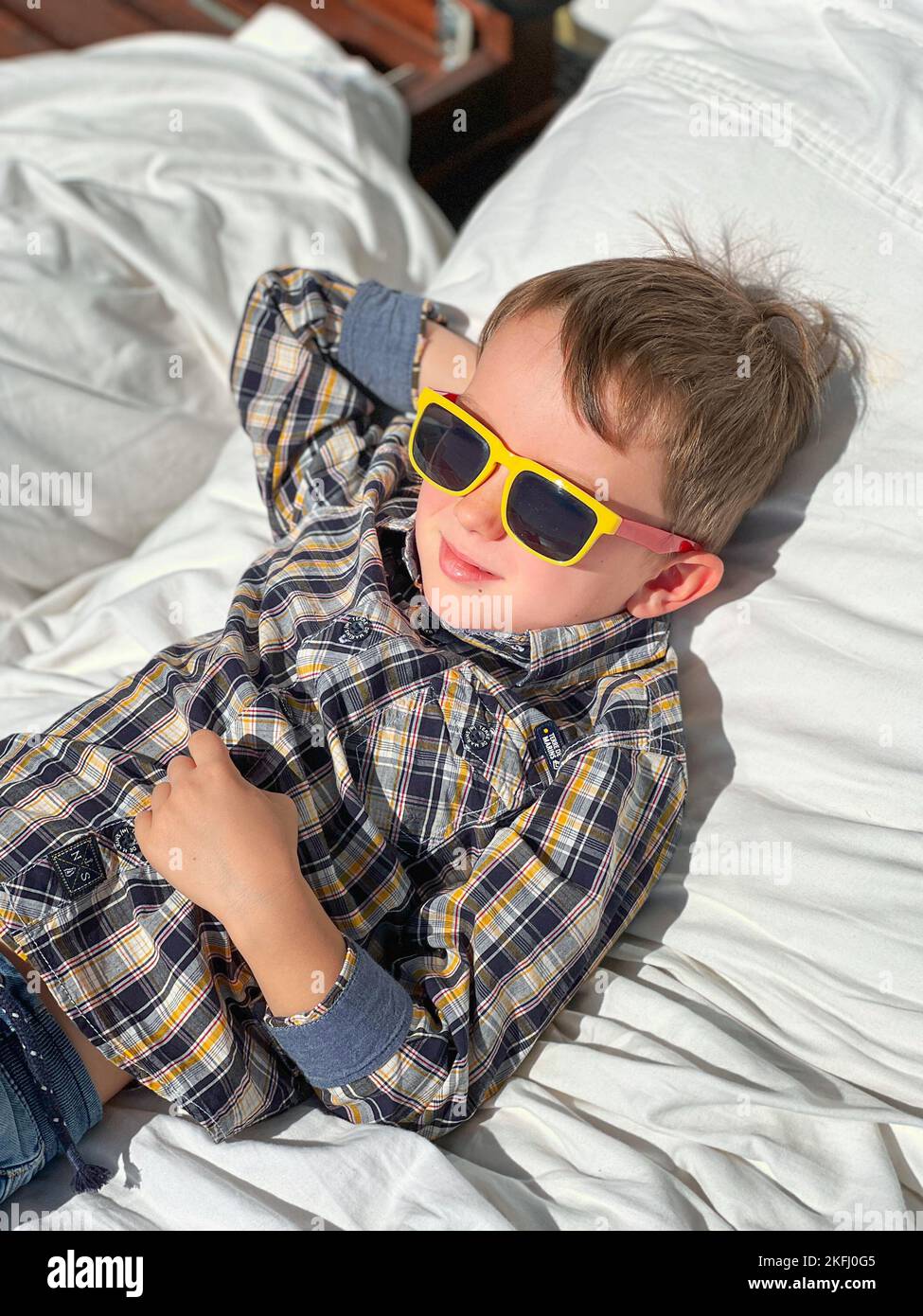 High angle view of cute Caucasian boy wearing sunglasses and relaxing ...