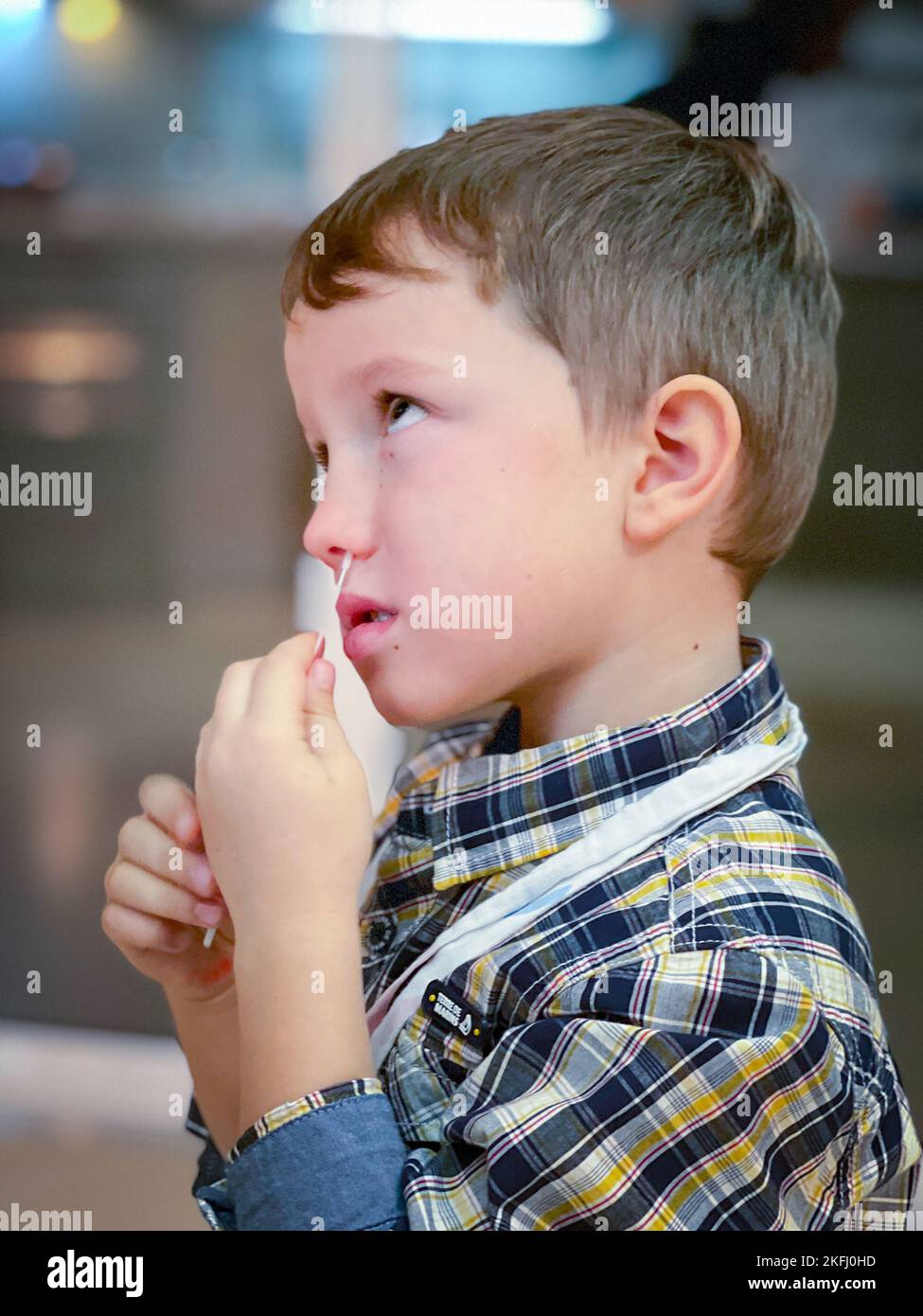 Side view of cute Caucasian elementary boy looking up and cleaning nose ...