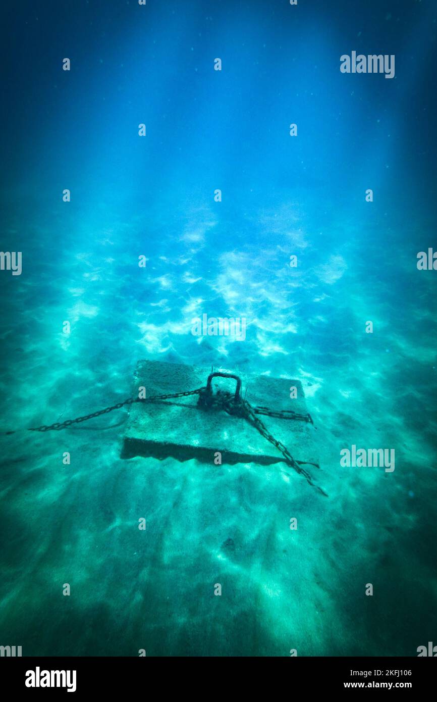 High angle view of chains tied to hook on concrete block over ocean ...