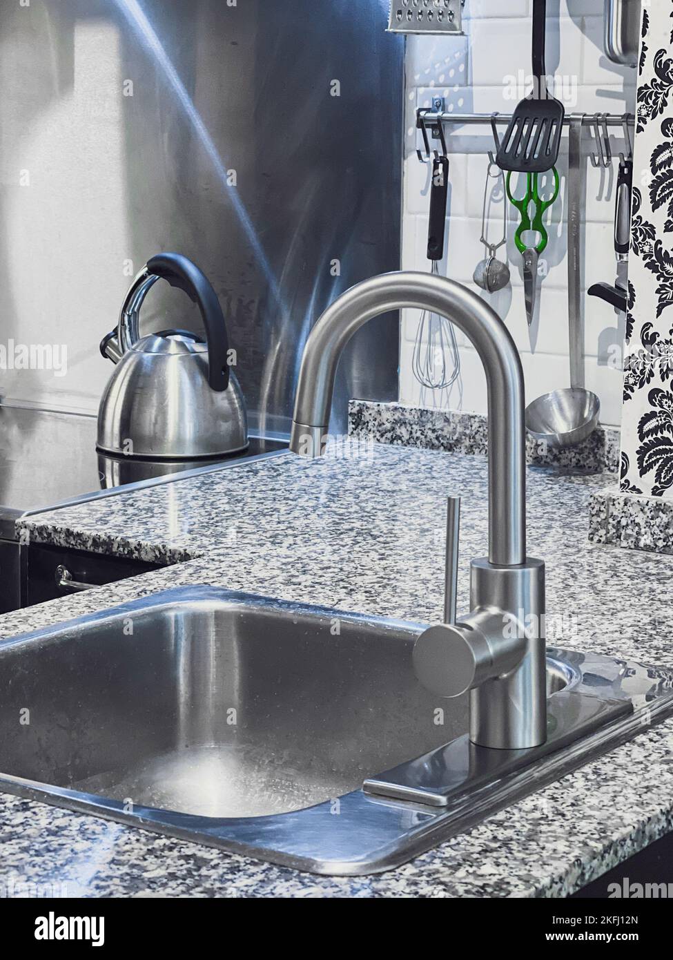 Stainless steel faucet with sink at kitchen island and utensils ...