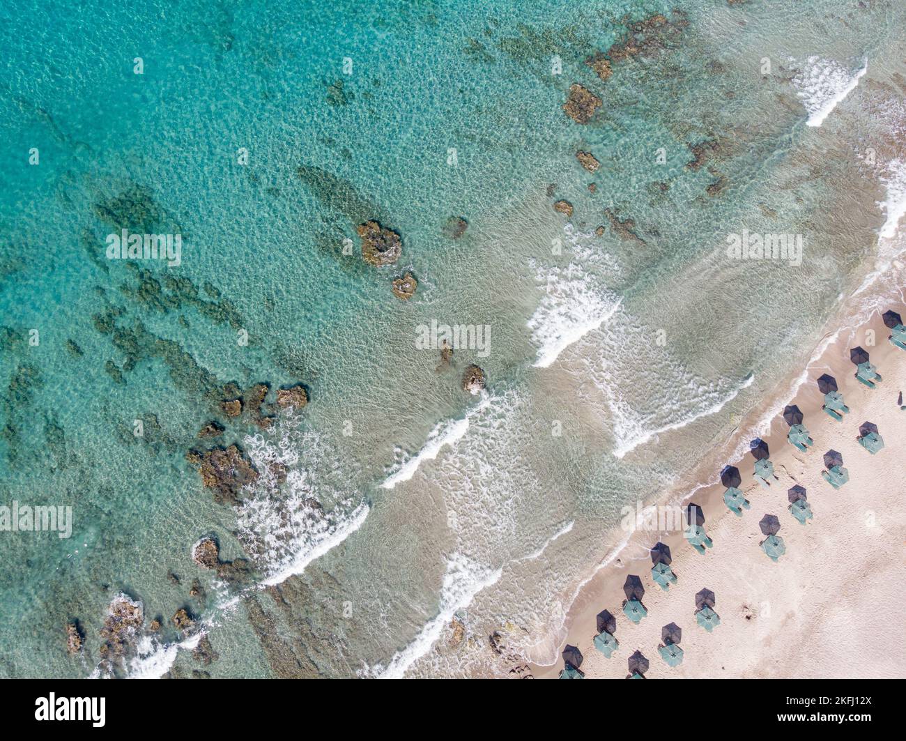 Aerial view of deck chairs and parasols arranged at beach by seascape ...