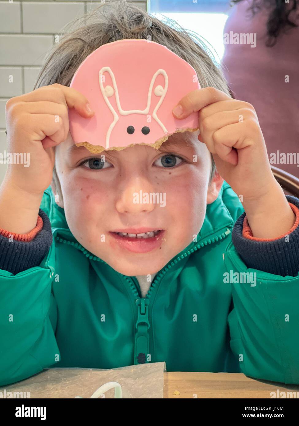 Close-up portrait of cute caucasian boy with bunny designed cookie ...