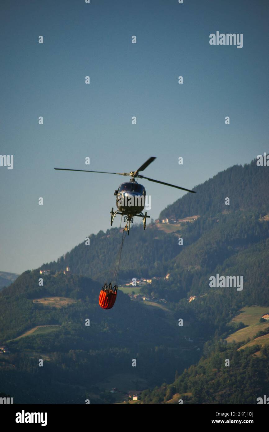 An aerial vertical of a helicopter collecting water to stop forest ...