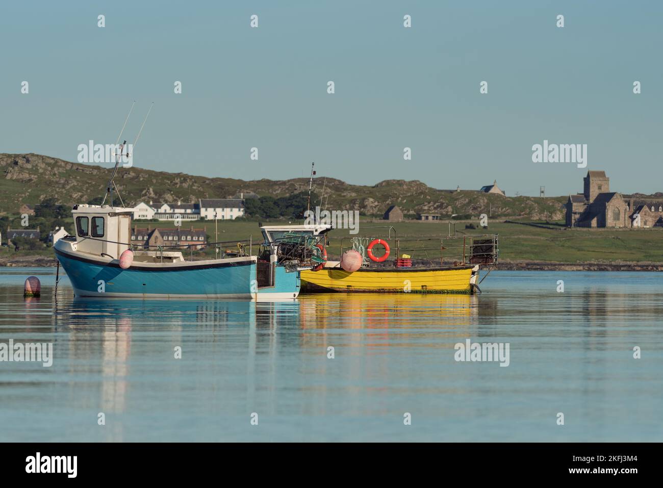 Tranquil boat scene. Blue and yellow old fishing boats with reflections ...